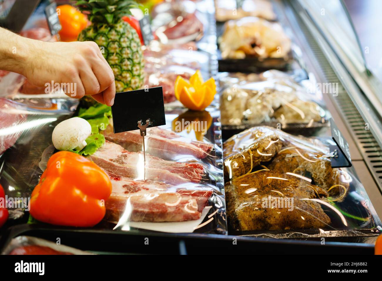 Male hand putting price tag on display of meat in shop, copy space ...