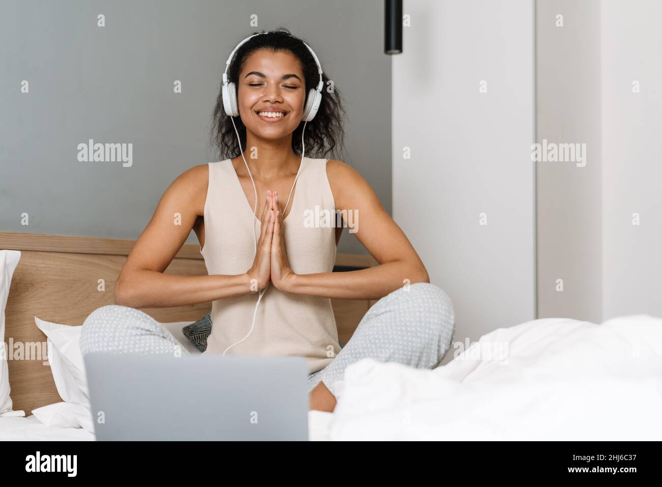 Happy Young African Woman Sitting In Bed With Laptop Computer In The