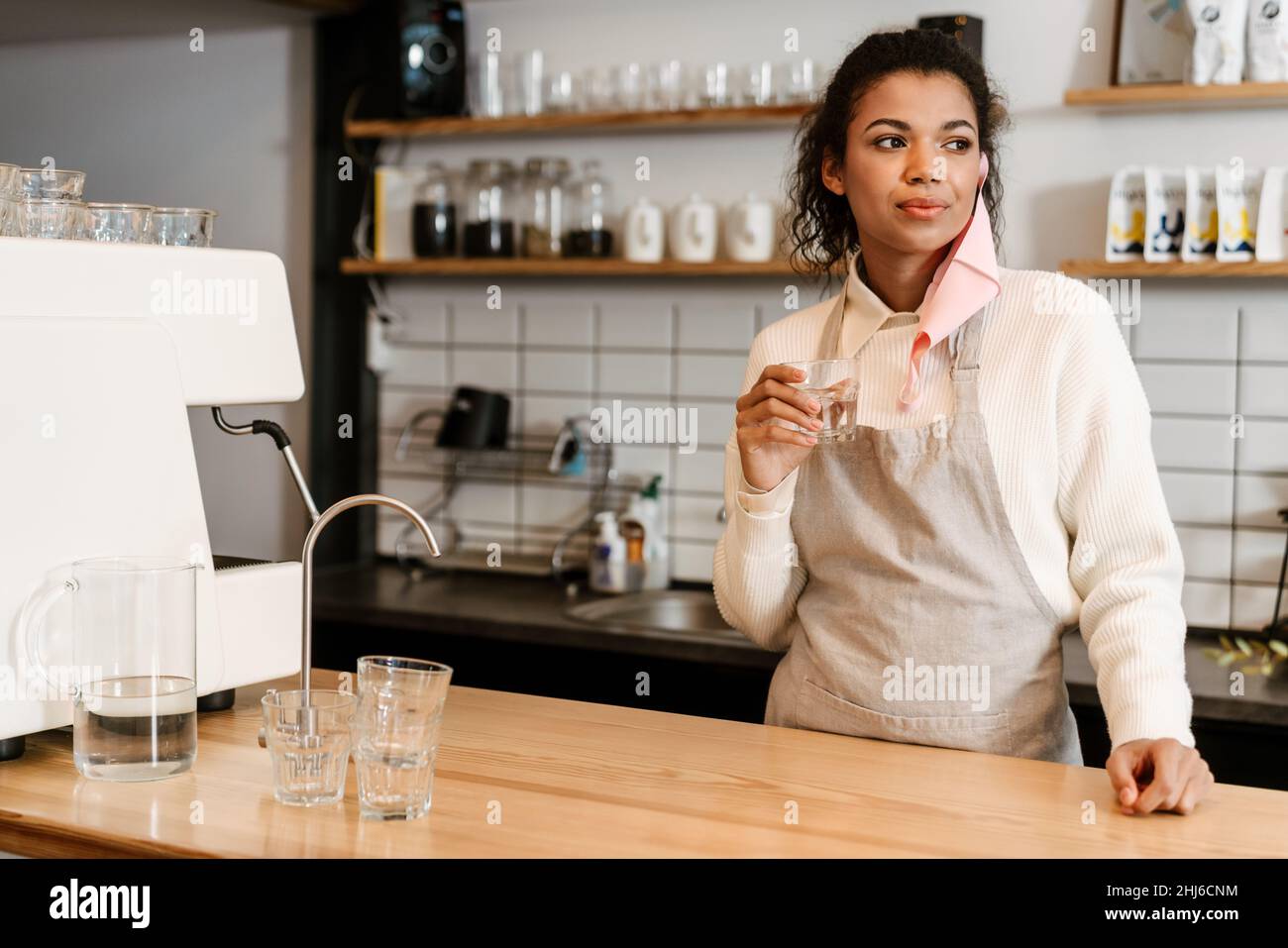 Young black waitress drinking water while working at cafe counter ...
