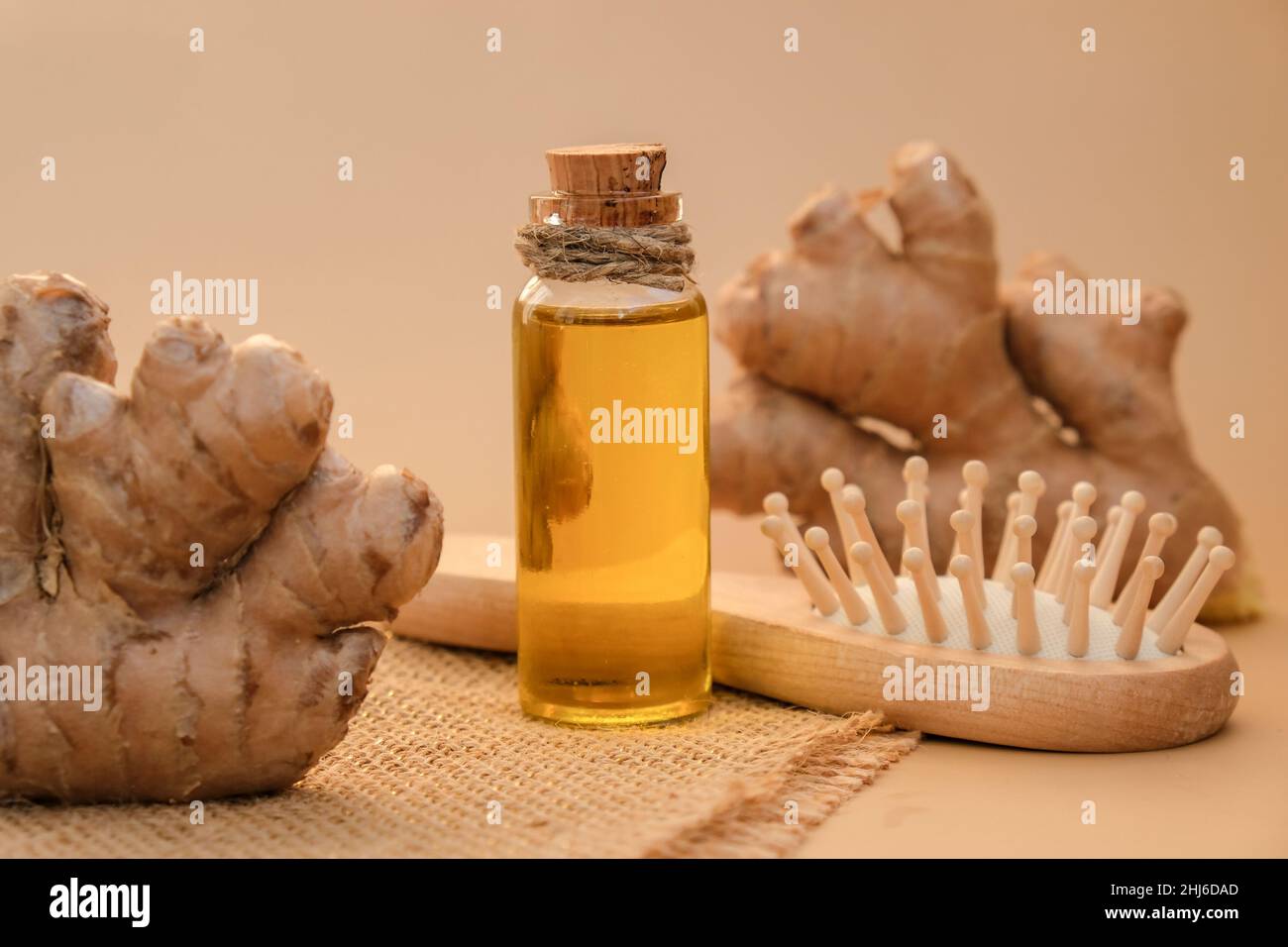 Glass bottle of essential ginger oil, ginger root on beige background ...
