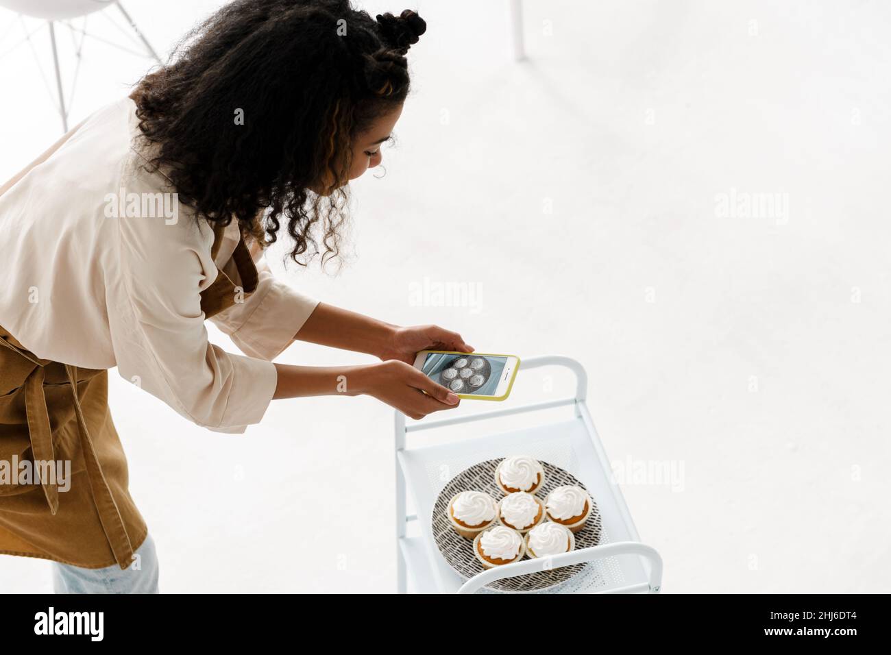 Black young woman in apron taking photo of her muffins at home Stock ...