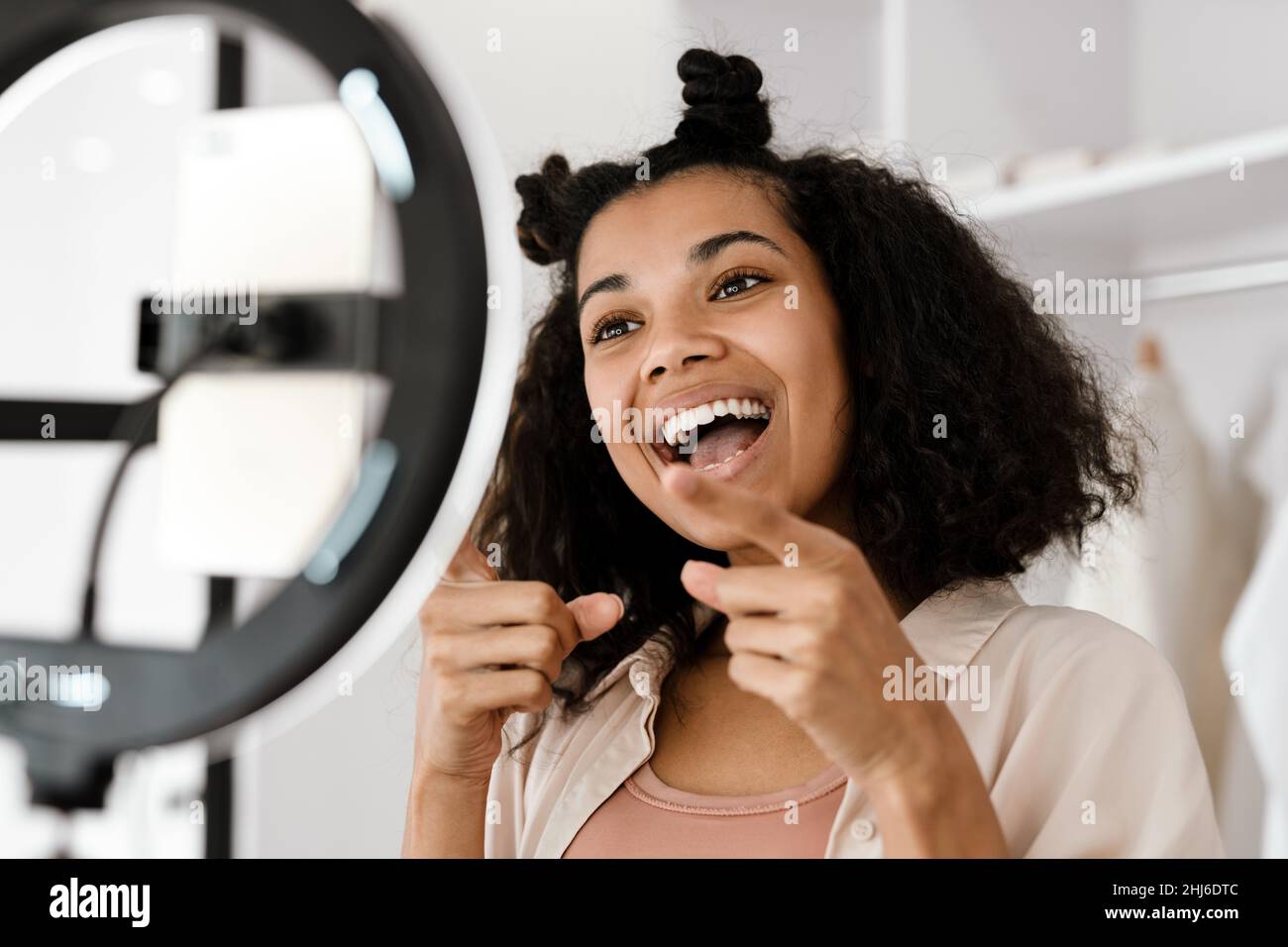 Happy young african woman influencer standing in front of a camera at ...