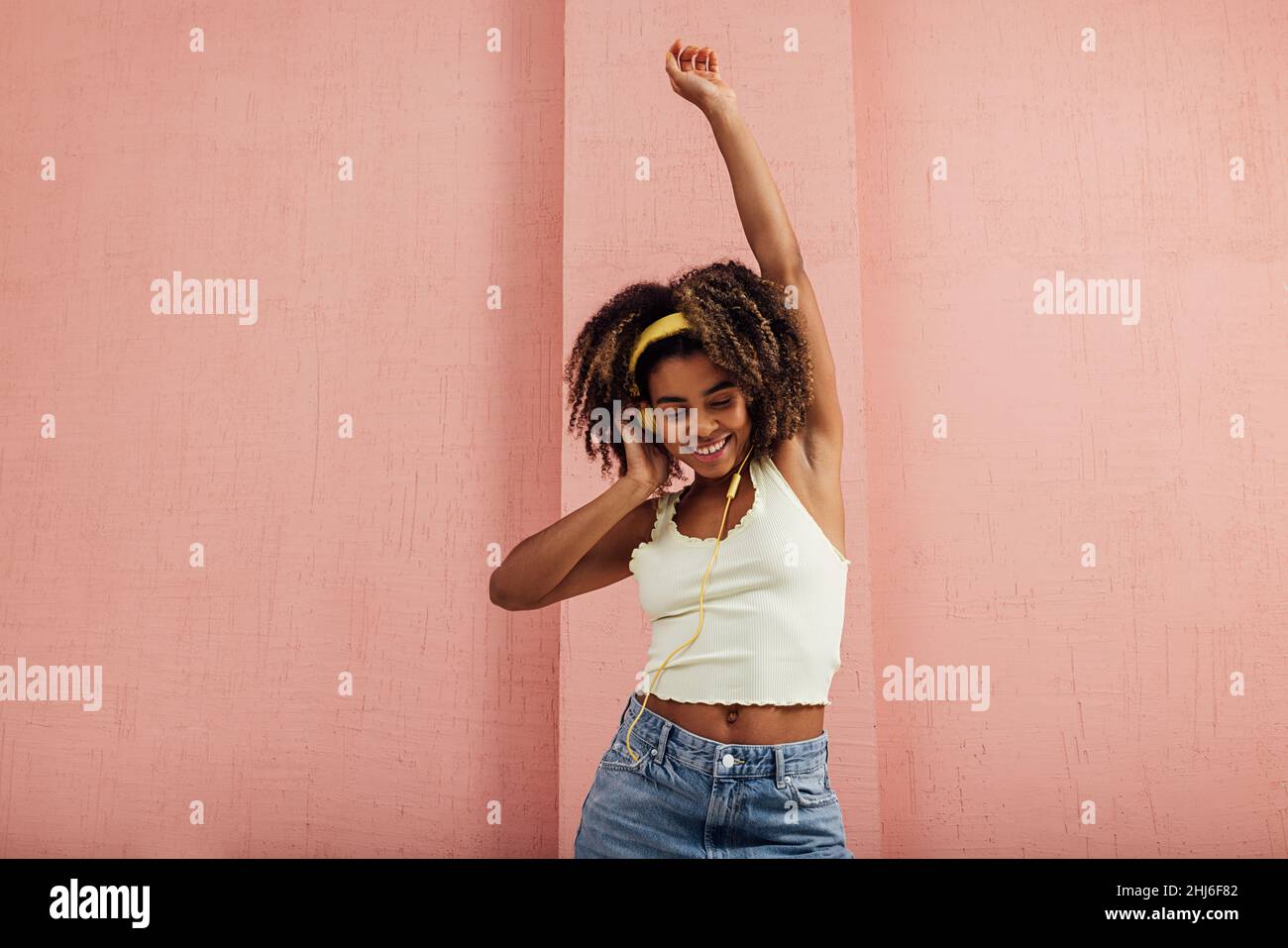 Smiling woman raising hand up while listening to music and dancing at a ...