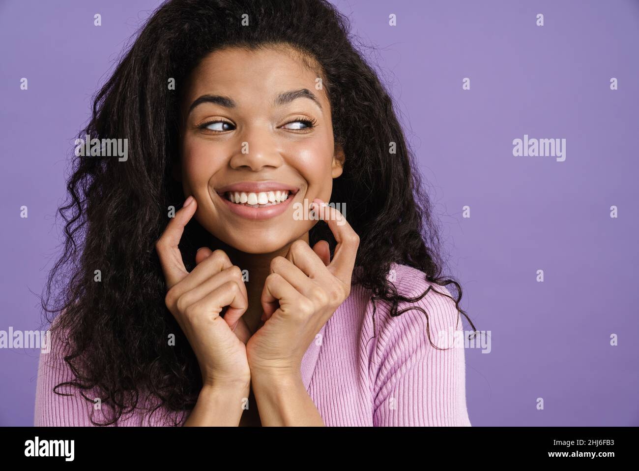 Young black woman smiling and pointing finger at her cheeks isolated ...