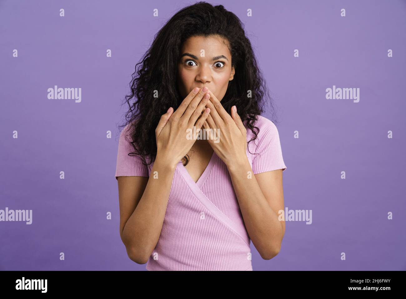 Young black woman covering her mouth while expressing surprise isolated ...