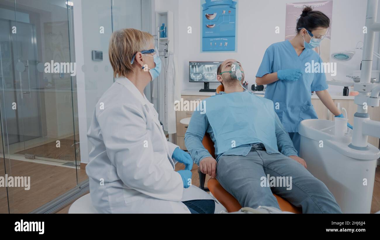 Dentistry assistant putting oxygen mask on face of patient to do ...