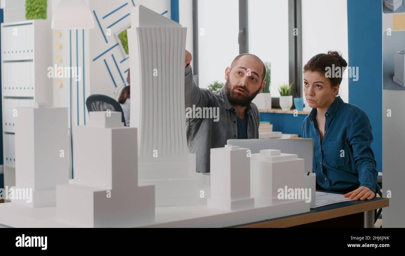 Team of architects designing building model on laptop in architectural ...
