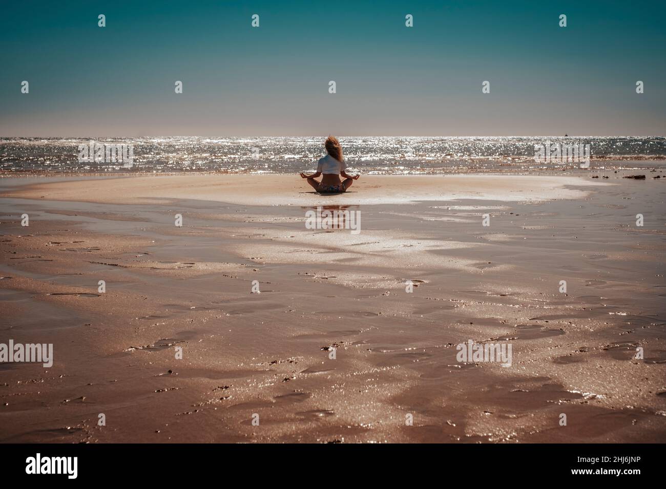 Inner balance life concept with woman sitting at the beach doing yoga ...