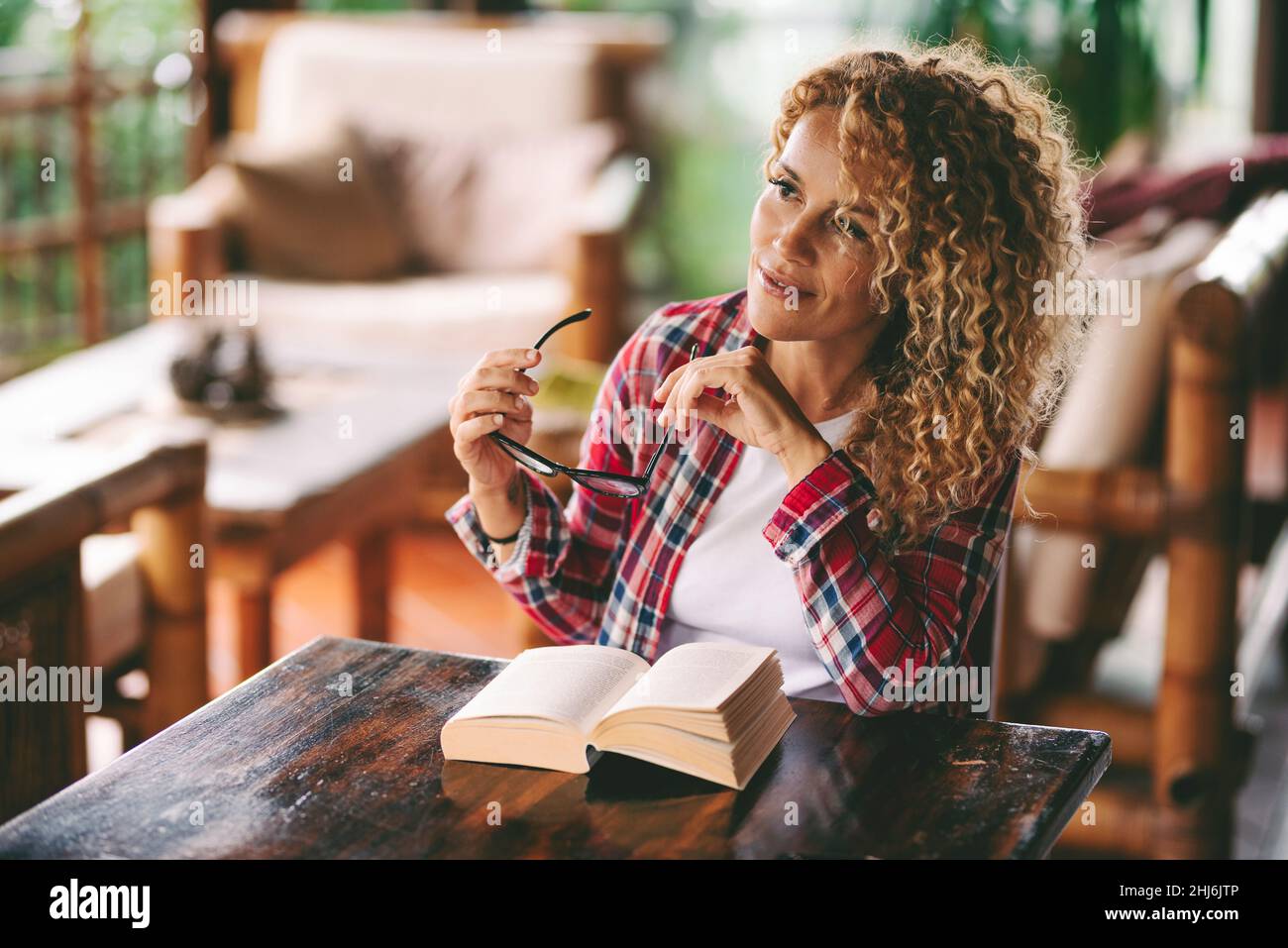 Cheerful adult pretty woman enjoy reading book at home sitting on the ...