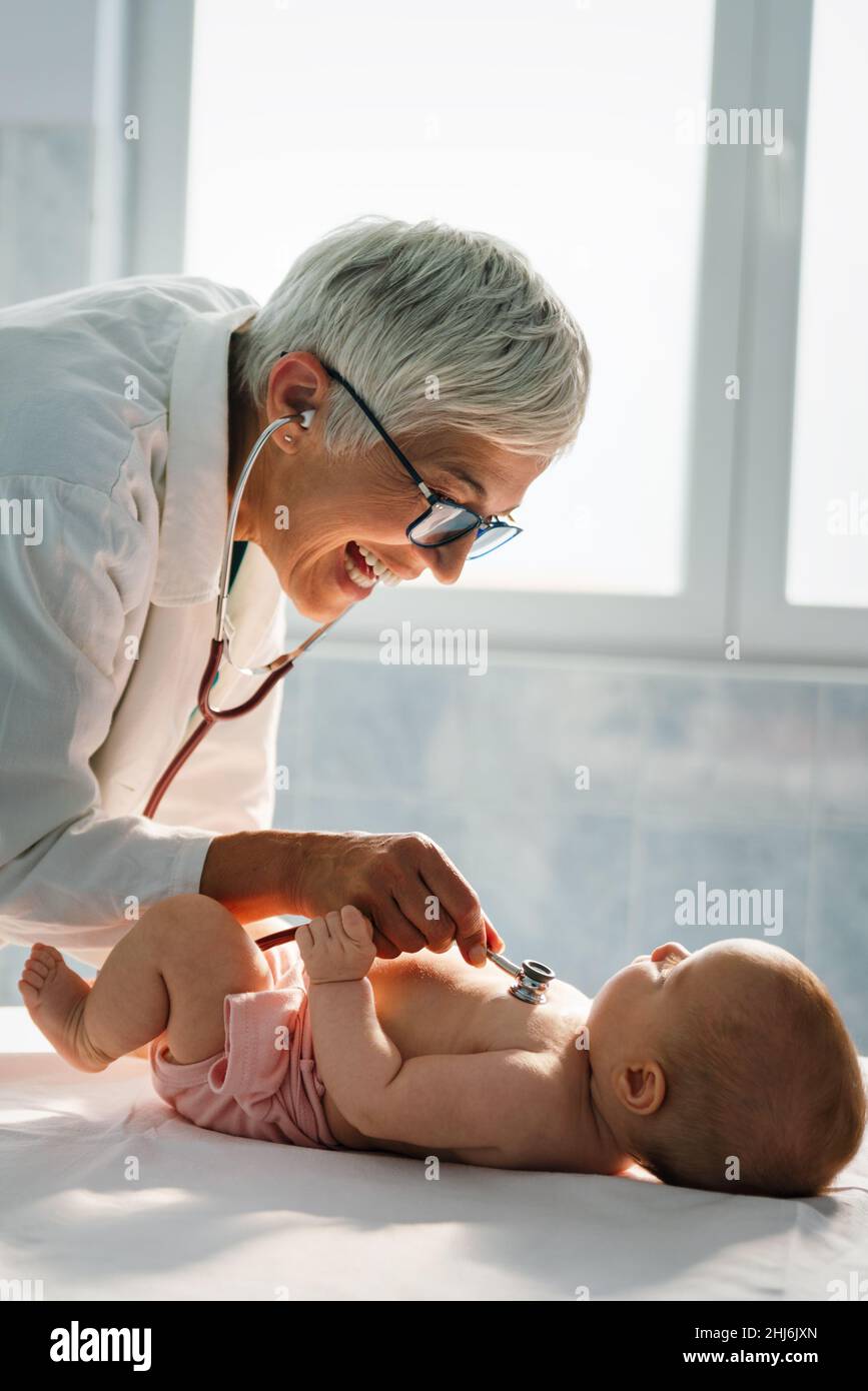 Happy pediatrician doctor with baby checking possible heart defect ...