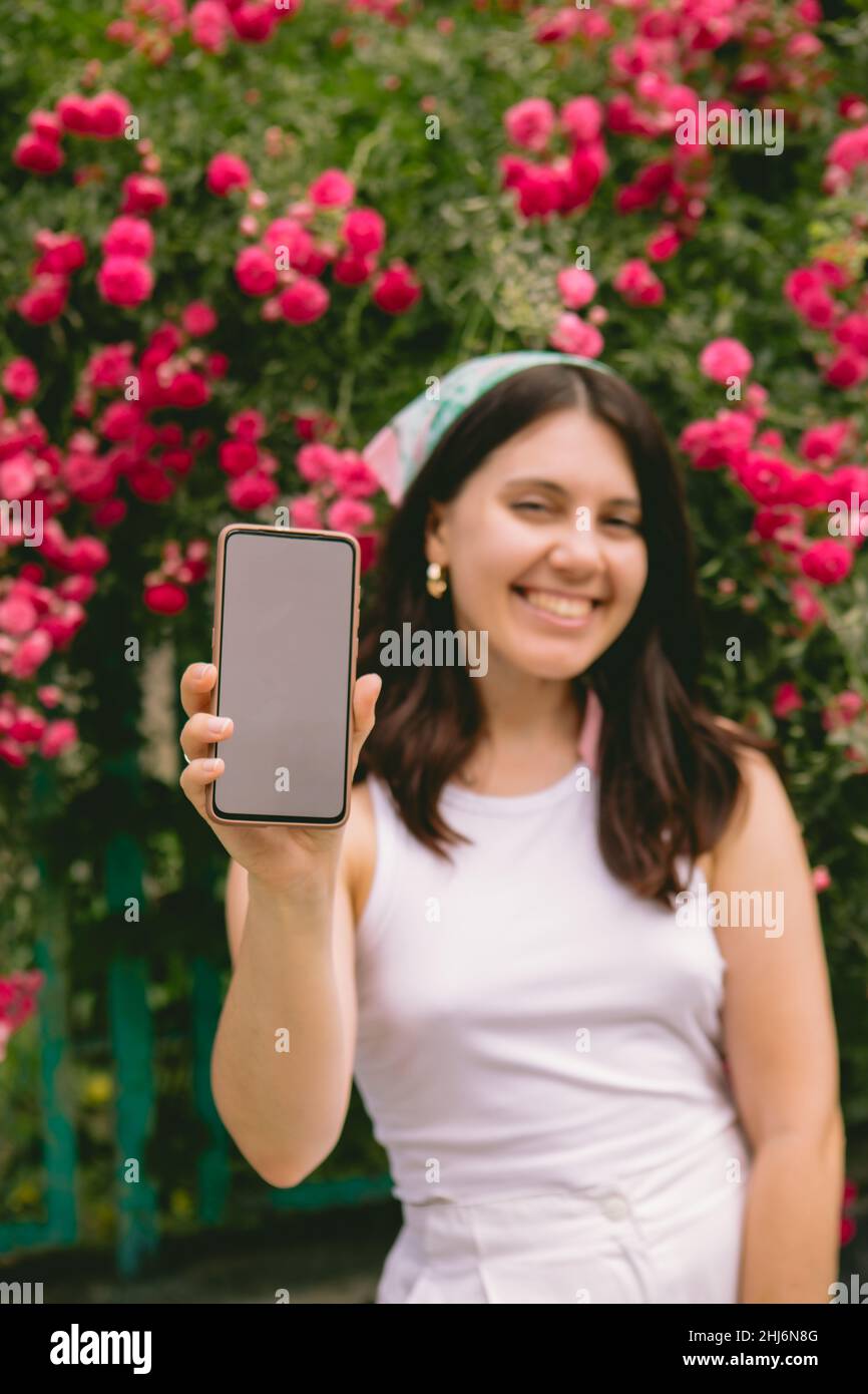 young pretty smiling woman holding phone with white screen copy space ...