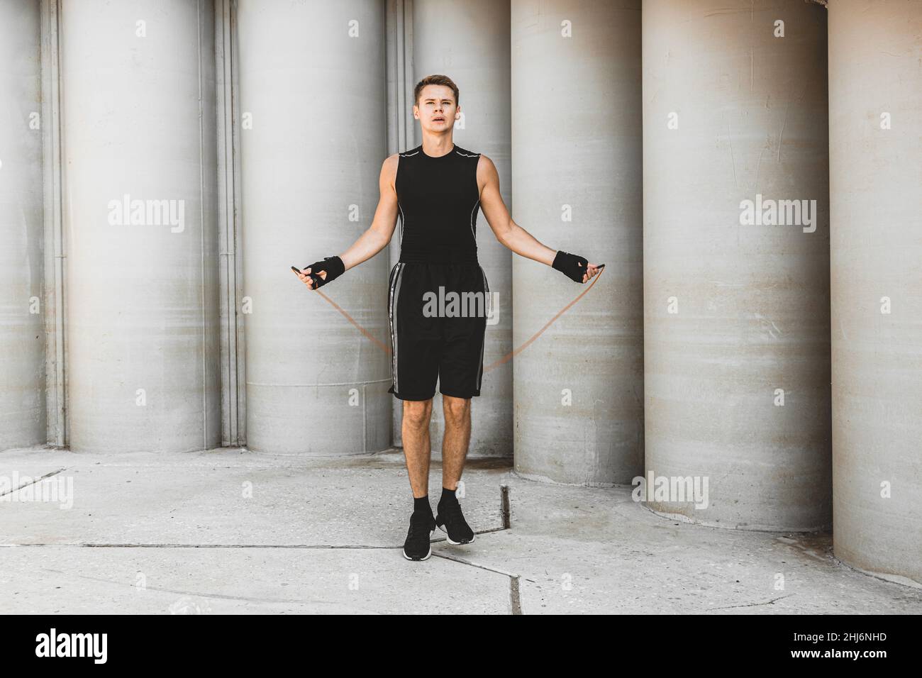 caucasian man fighter training hard in the outdoors.. Man using rope ...