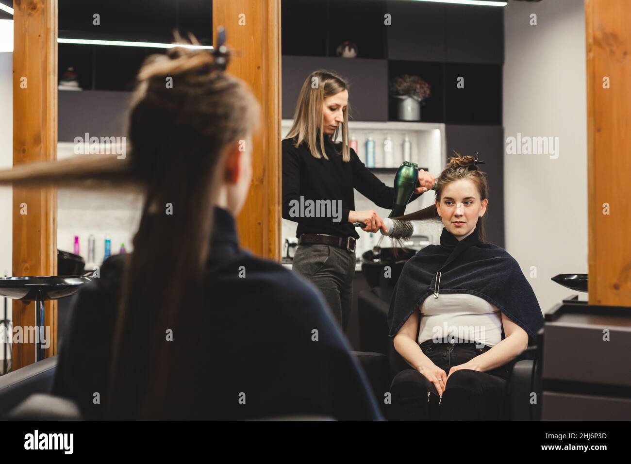 Master woman hairdresser dries the girl's hair with a hairdryer after ...