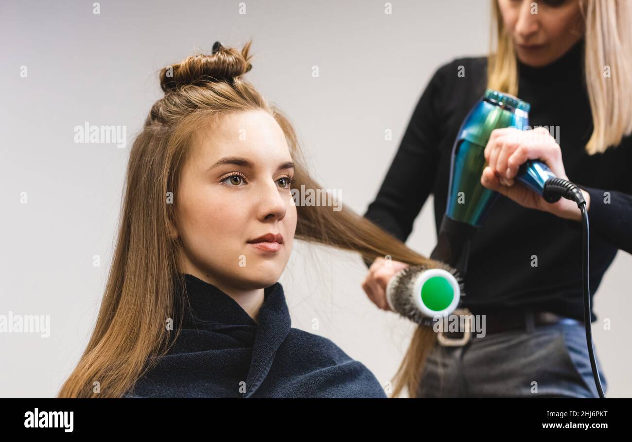 Master woman hairdresser dries the girl's hair with a hairdryer and ...