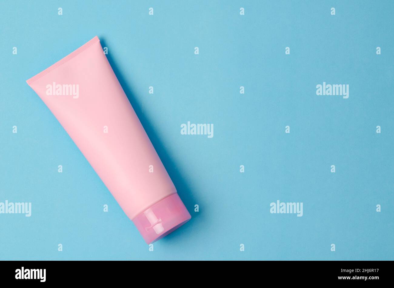 Empty a cosmetic pink tube of cream on blue background with empty space ...