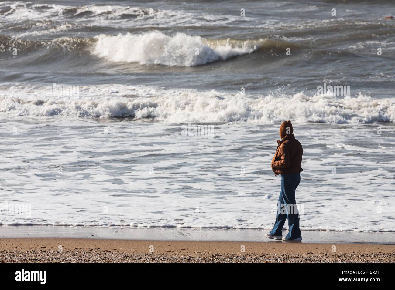 The woman walks along the beach and looks at the restless deep sea ...