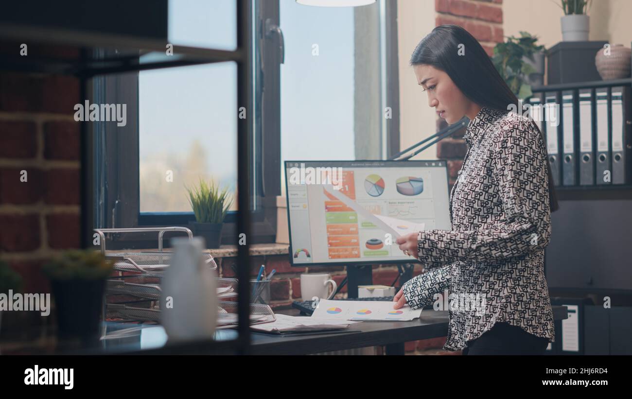 Close up of woman comparing data on papers with computer to work on ...