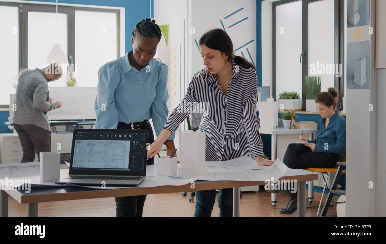 Team Of Workmates Looking At Building Model And Blueprints Plans On Table Women Architects