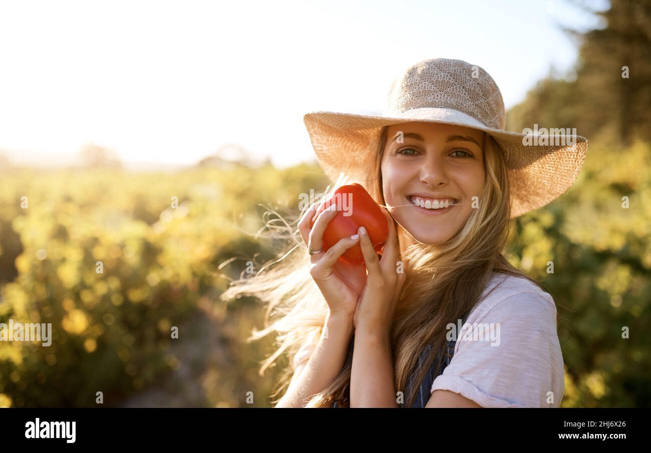 Fresh food is the best food. Shot of a young woman working on a farm ...