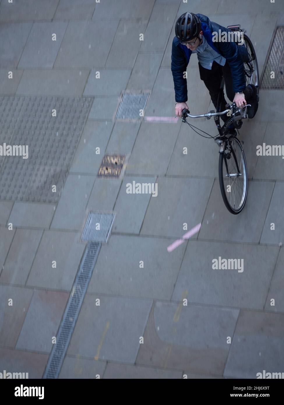 Cyclist riding bike on pavement, Barbican, London Stock Photo - Alamy