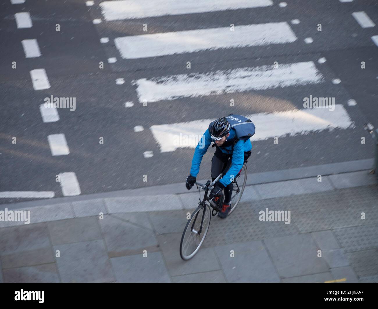 Cyclist riding bike on pavement, near pedestrian zebra crossing ...
