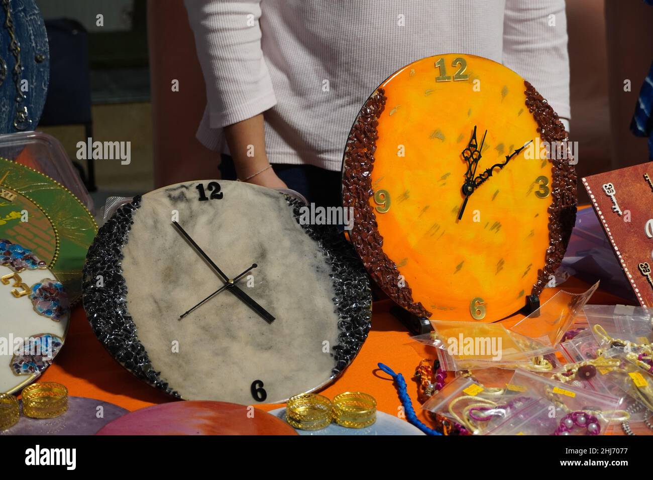 Many different wall clock displayed for sale. Round frame orange and ...