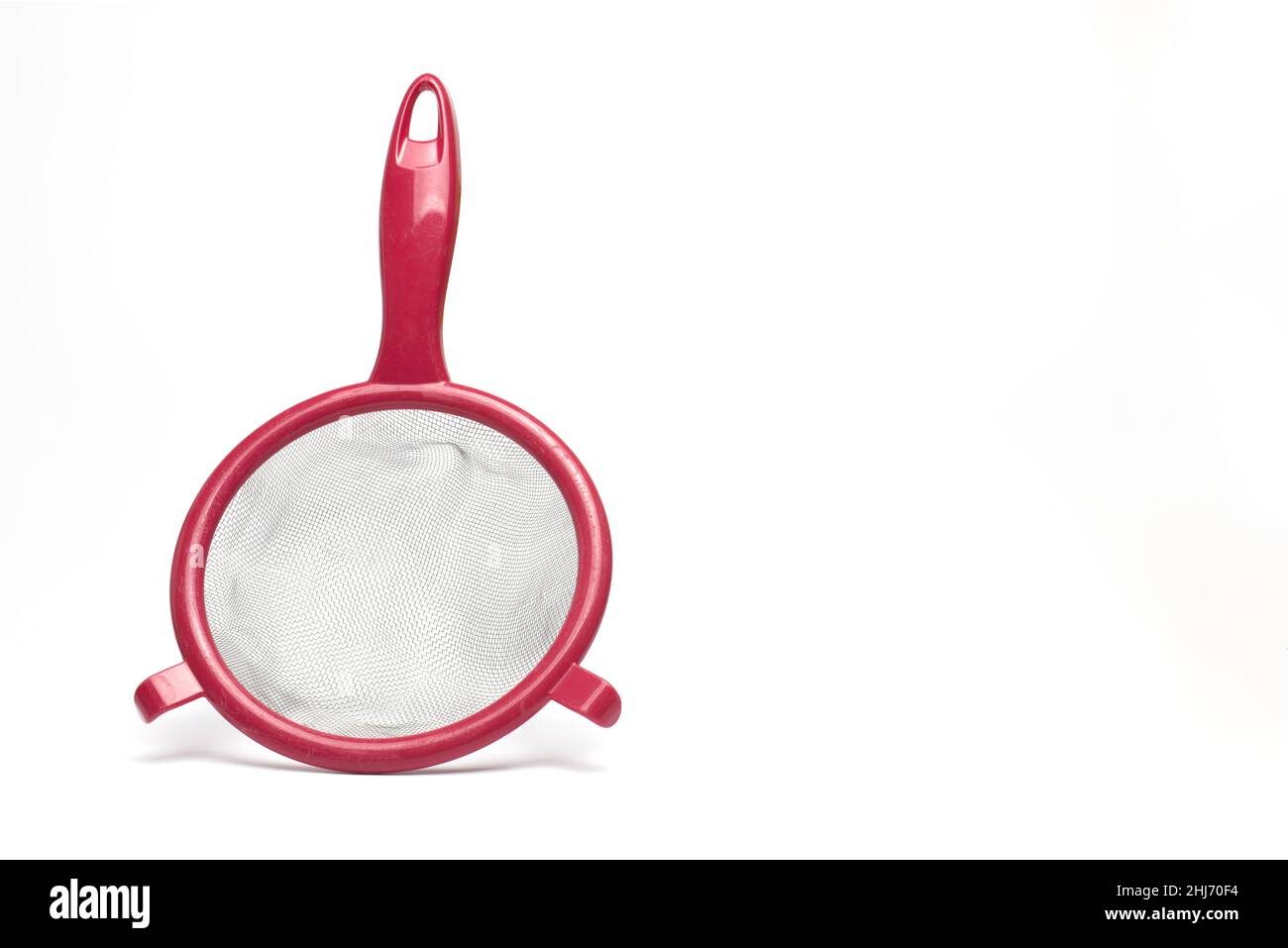 Close up of red kitchen strainer for separating fine and coarse parts ...