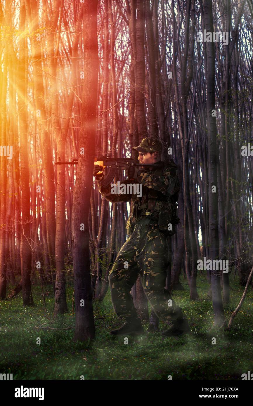 Army soldier in camouflage aiming with his gun, hiding in the forest ...