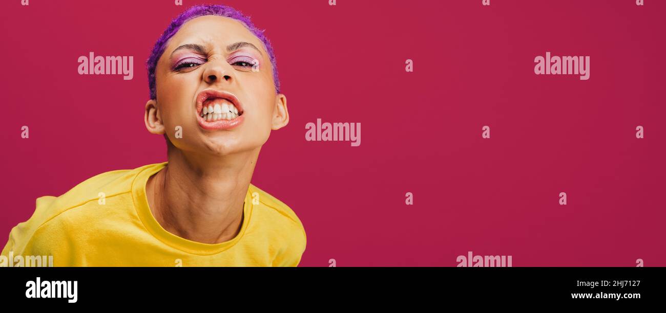 Quirky young woman making a face in a studio. Fashionable young woman ...