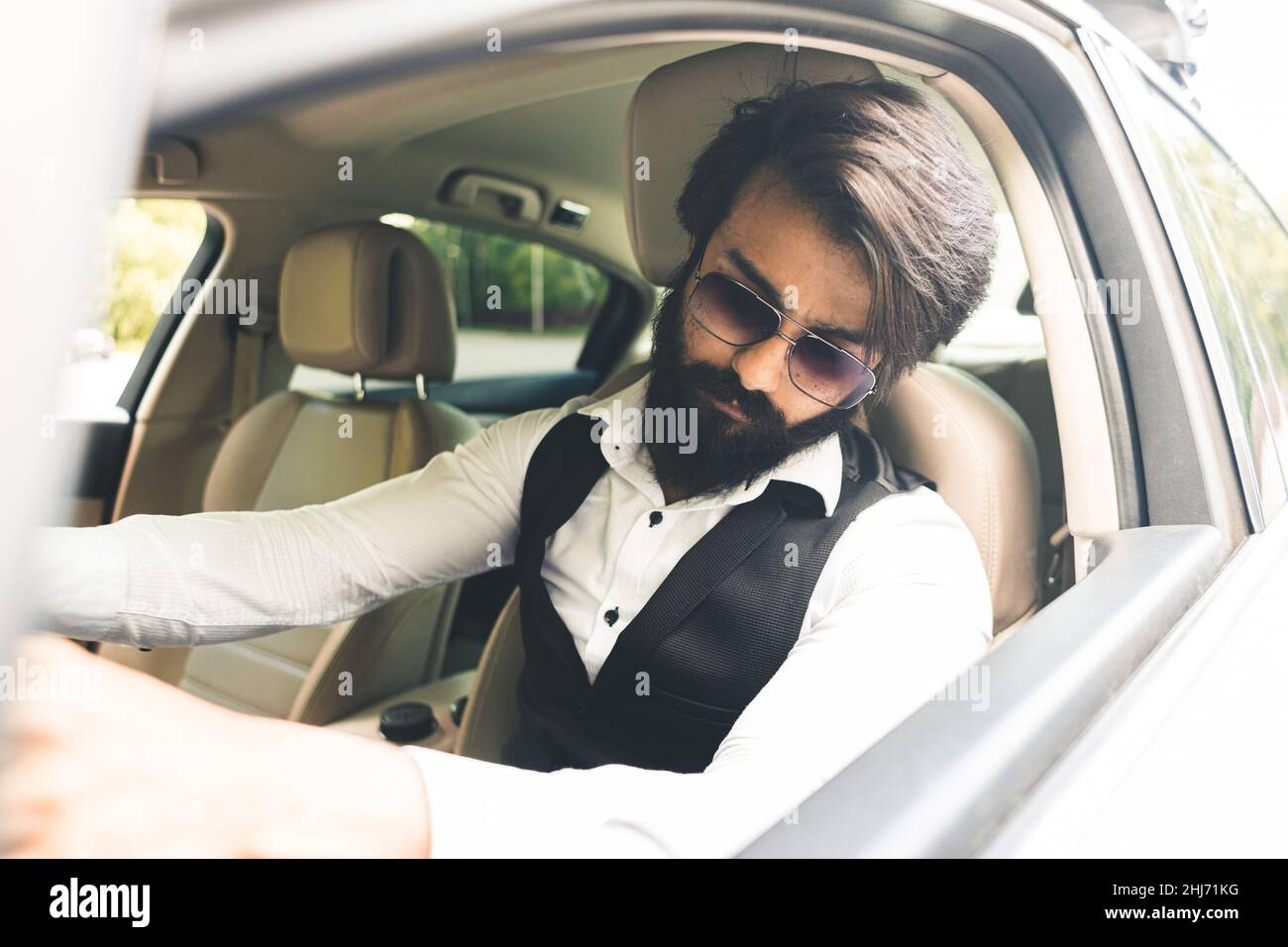 Stylish and successful Indian in a stylish suit driving a luxury car ...
