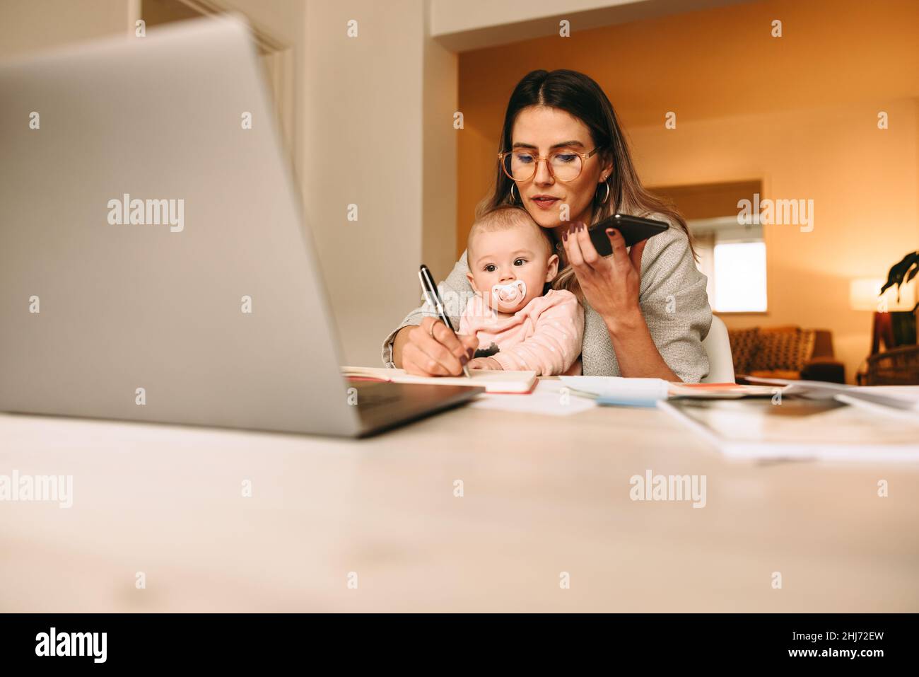 Working mom making notes during a phone call with her clients ...