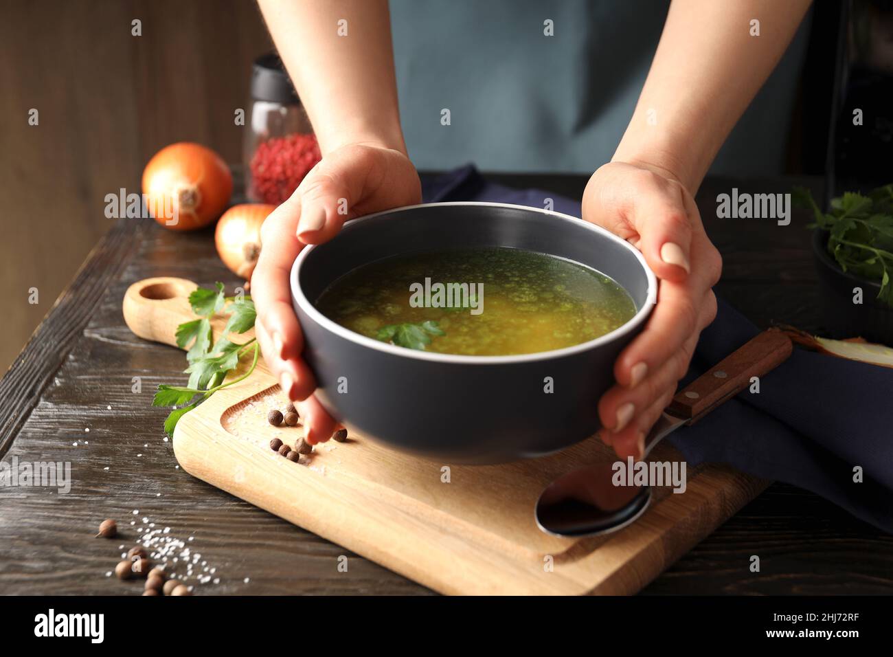 Female hands hold chicken soup or broth on a wooden table Stock Photo ...
