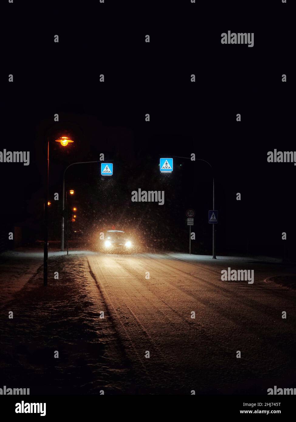 Car driving down a road at night while it is snowing Stock Photo - Alamy