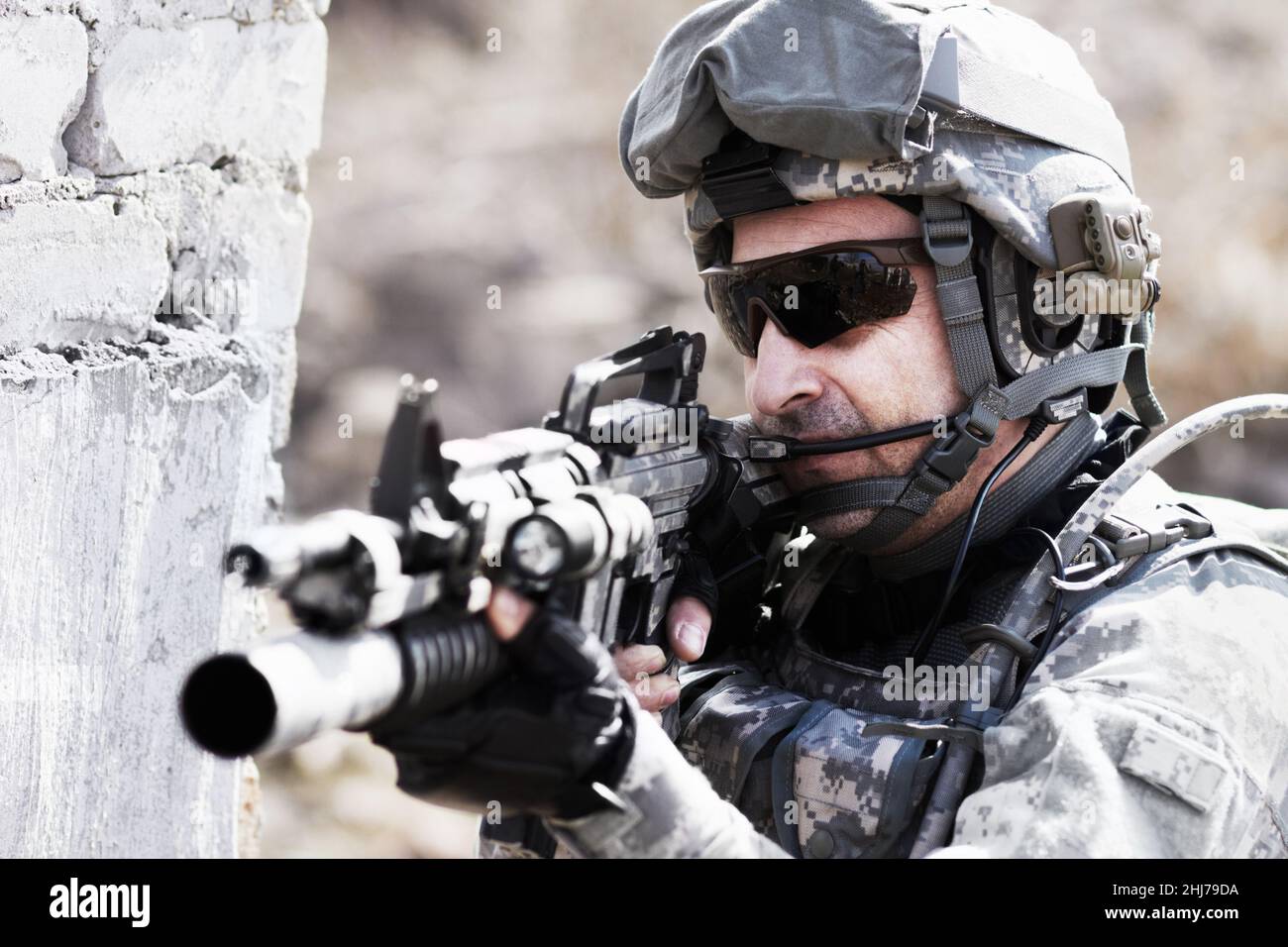 Taking aim. A soldier crouched down next to a broken down wall and ...