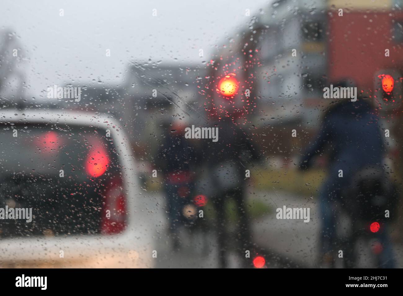 Raindrops on the windshield while waiting in front of a red traffic ...