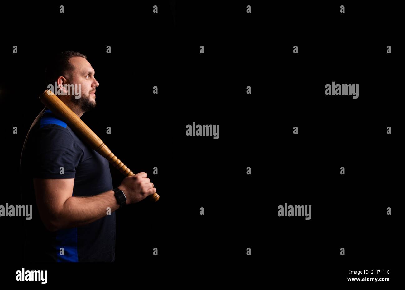 Young man with a baseball bat on a dark background. Bouncer, security ...