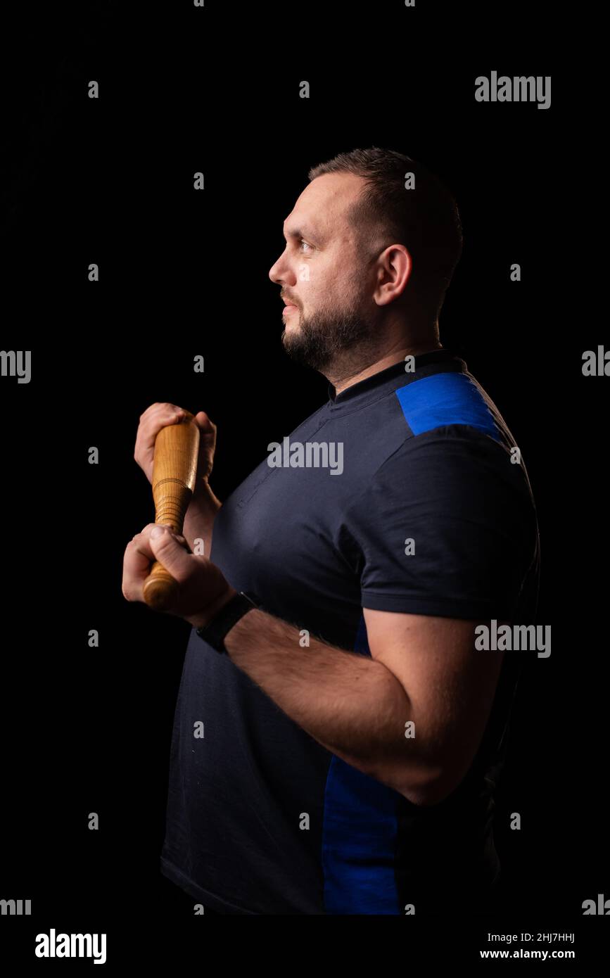 Young man with a baseball bat on a dark background. Bouncer, security ...