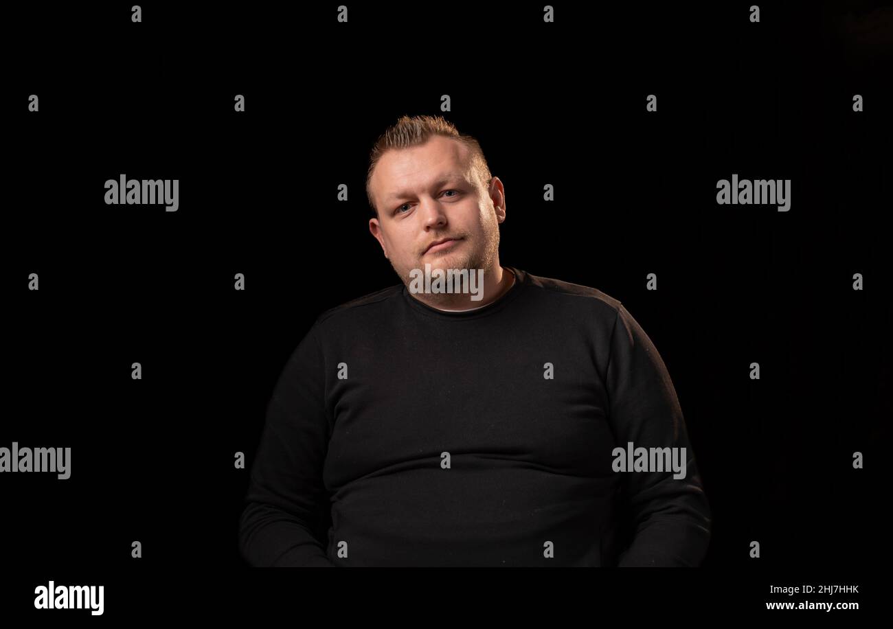 Portrait of a young man with a beard. Dark background. A slightly ...