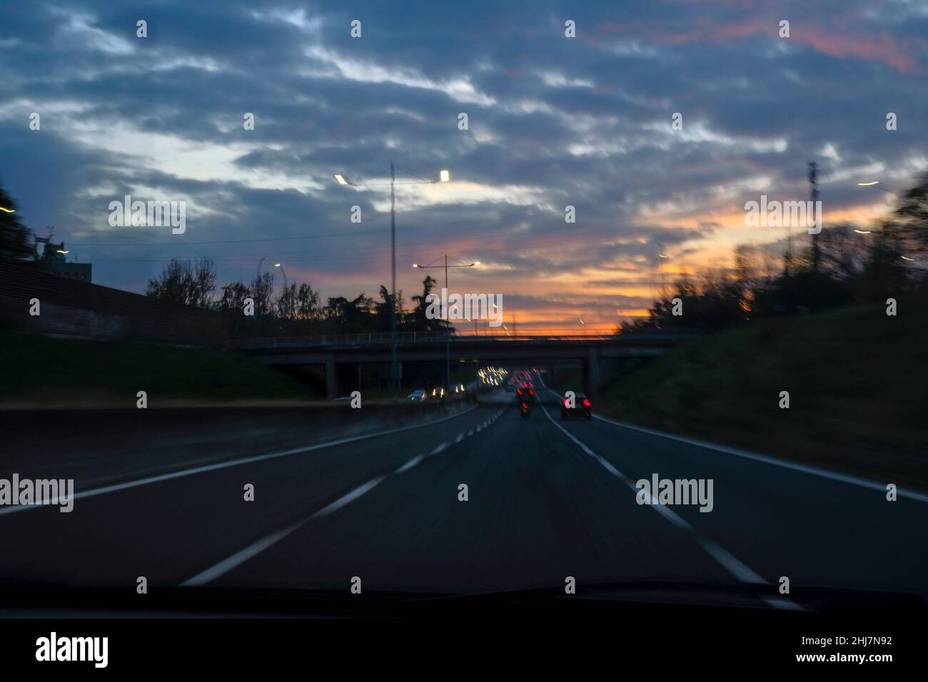 sunset over the highway full of cars across the bridge and sky full of ...