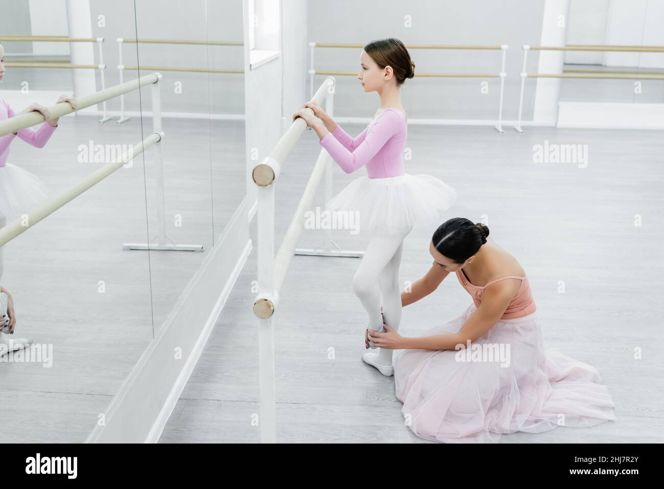 side view of girl training in ballet school near mirrors and dance ...