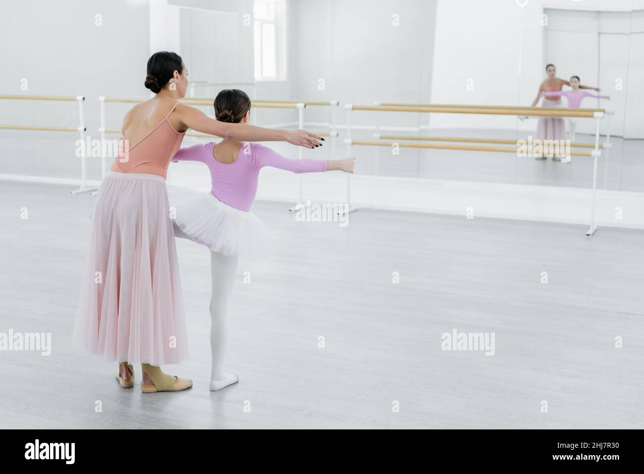 back view of girl training in ballet school near mirrors and young ...