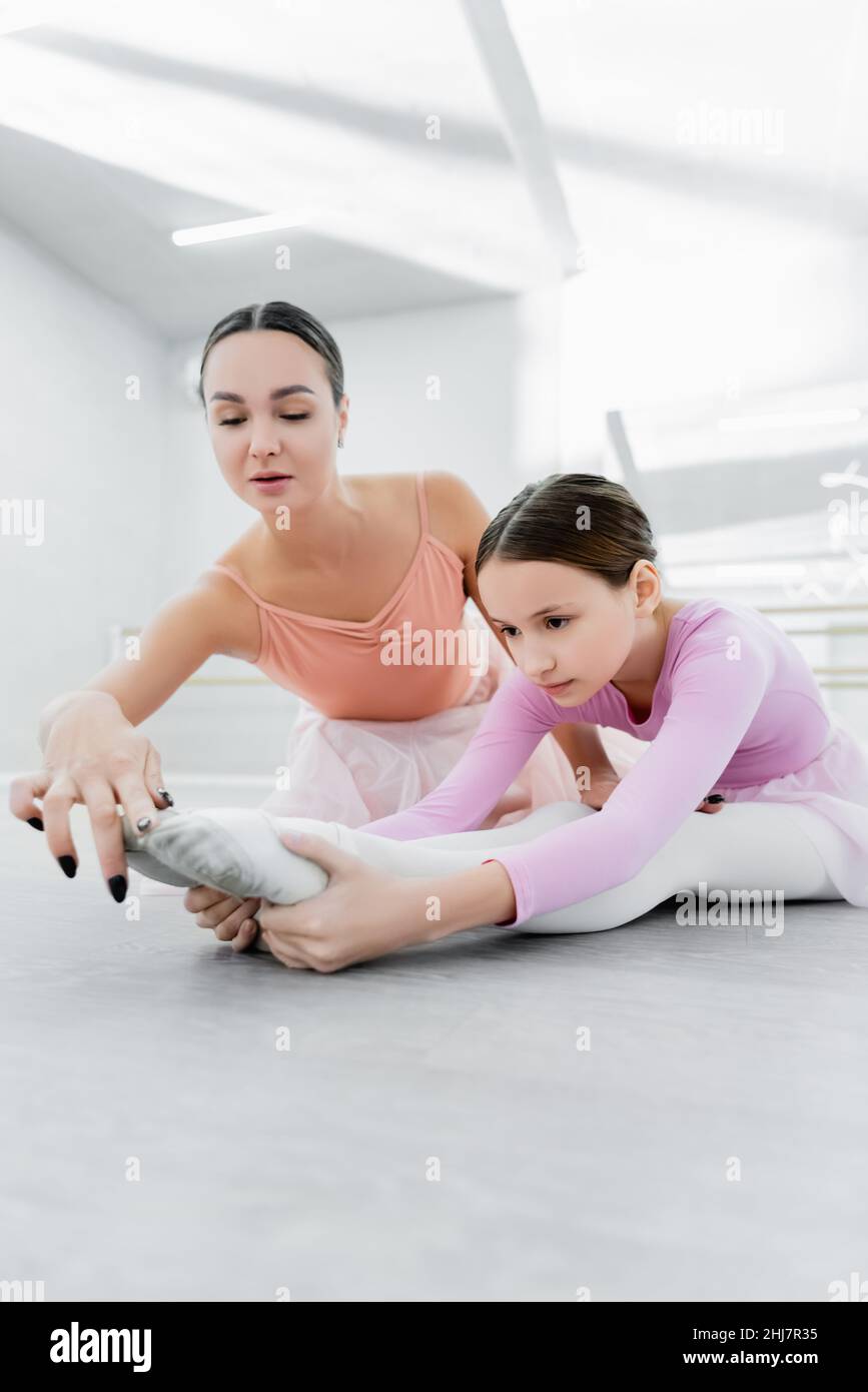 choreographer assisting girl stretching on floor in ballet school Stock ...