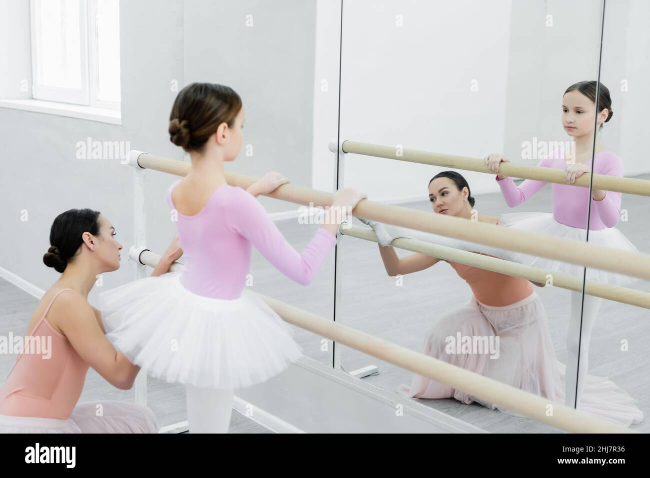 child looking in mirror while training at barre near young ballet ...