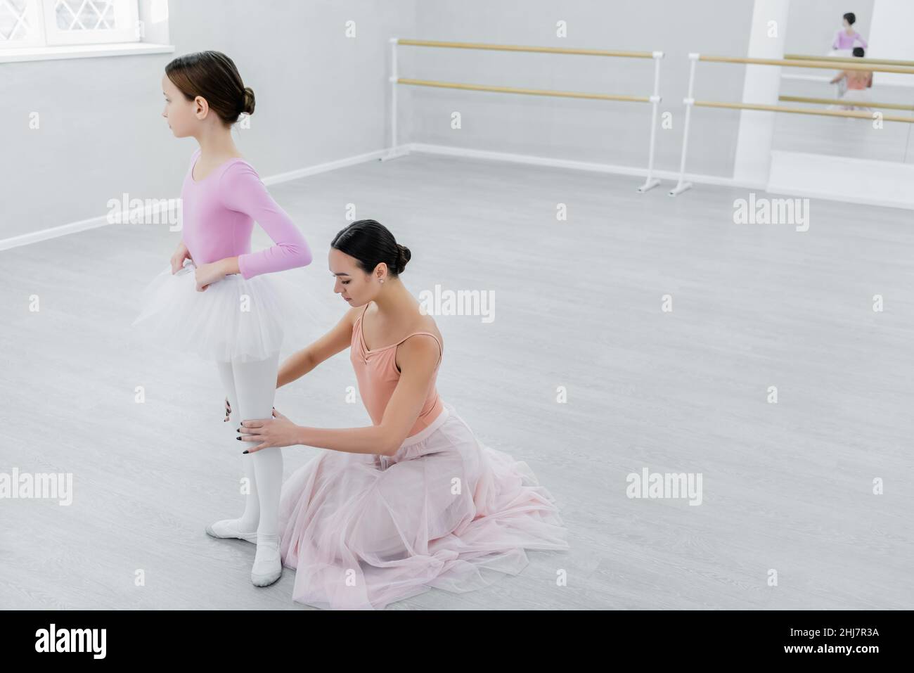 ballet master touching knees of girl during rehearsal in dancing hall ...