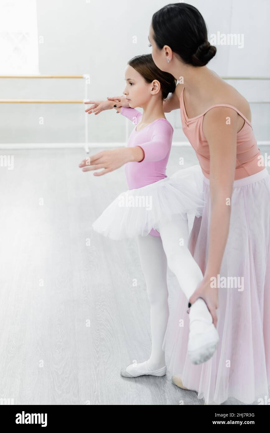 side view of girl learning choreographic elements near ballet master ...