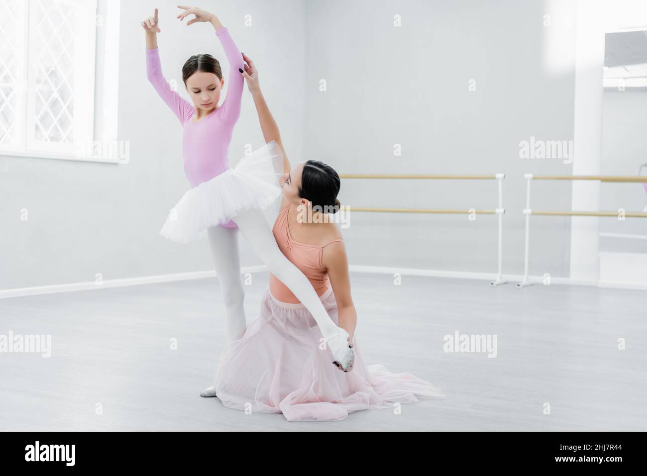 preteen girl practicing choreographic elements near young ballet ...
