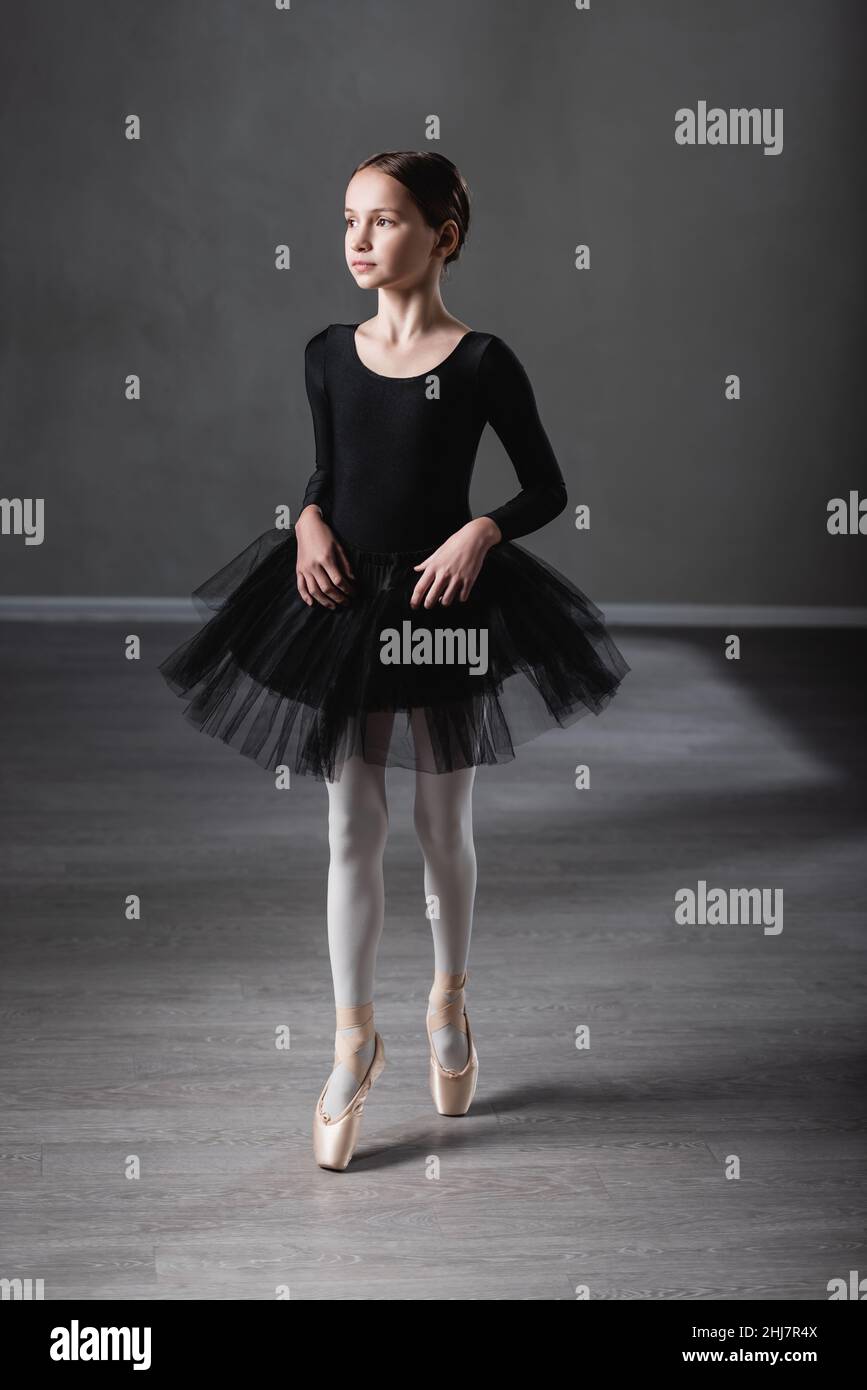 preteen girl in black tutu and pointe shoes standing on toe while ...