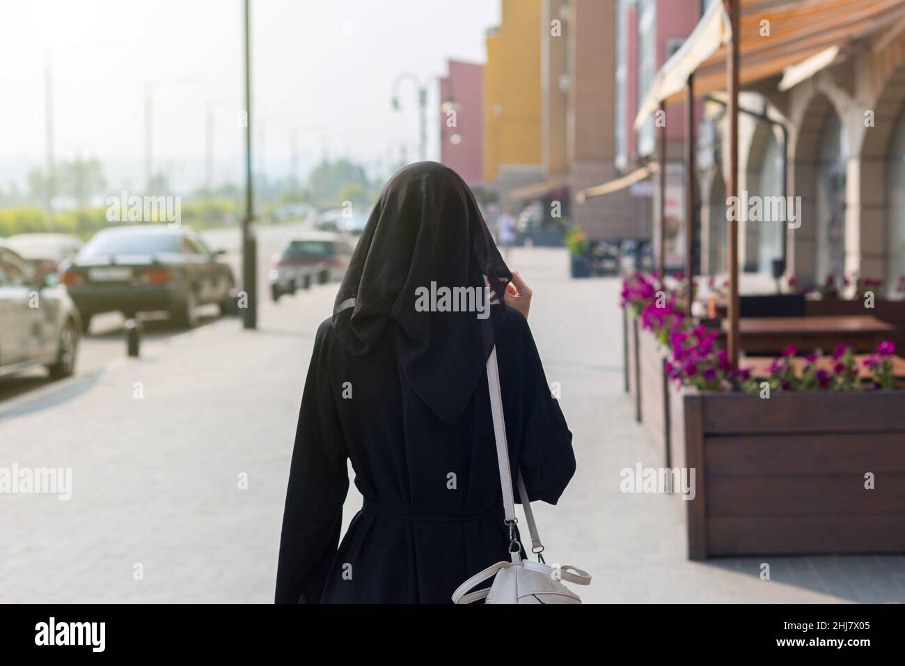 A single Muslim woman walks through empty big city rear view Stock Photo - Alamy