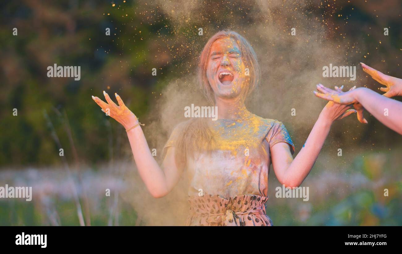 Friends sprinkle their cheerful girlfriend with multi-colored powder ...