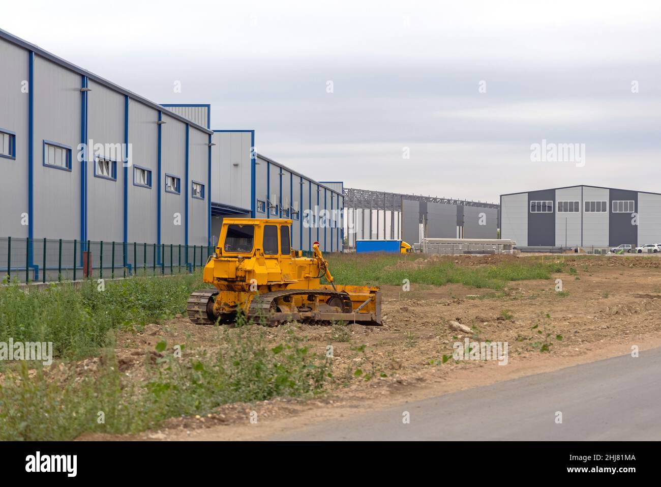 Yellow Earth Mover Construction Machine Behind Warehouse Buildings ...
